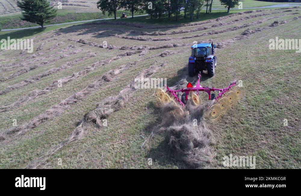 hay rake being pulled by tractor in field during harvest time near ...