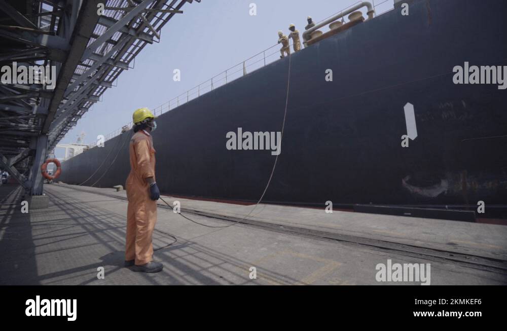Longshoreman At Work Mooring Large Cargo Ship At The Port. wide shot ...