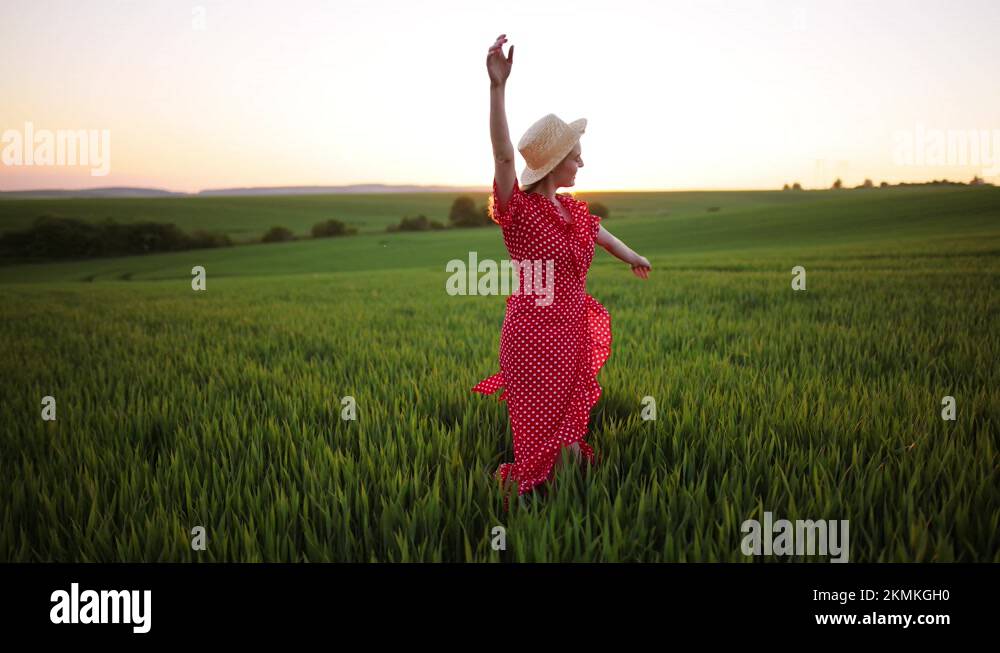 Young woman happily walking in slow motion through a field touching ...