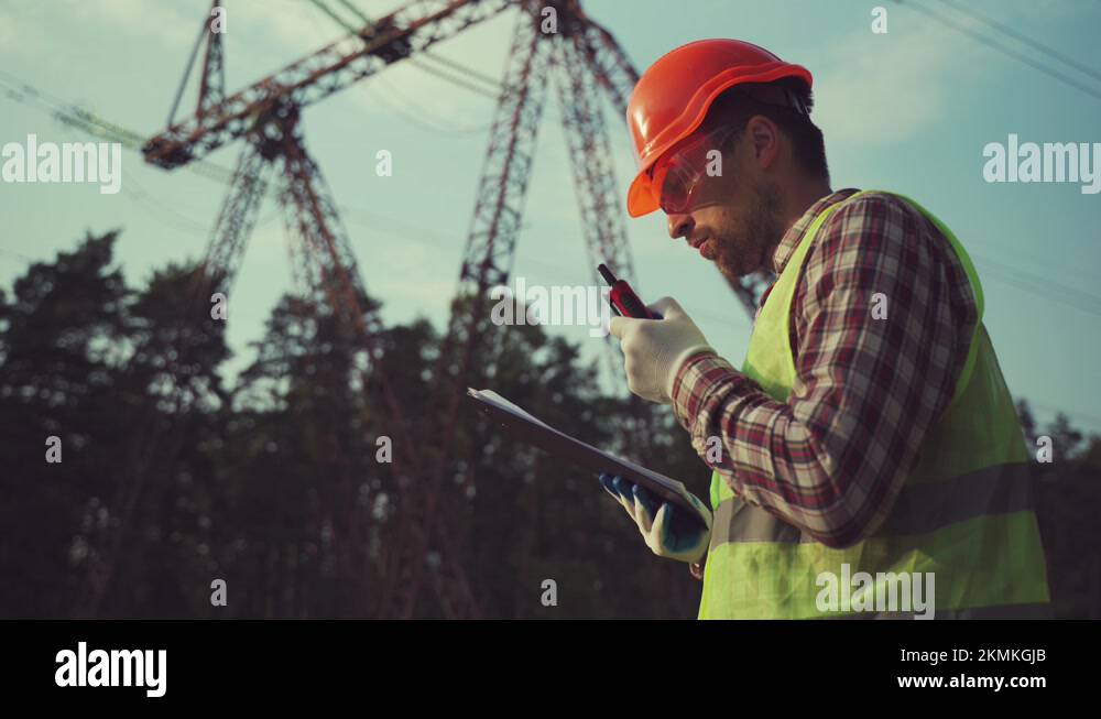 Electrical engineer wearing hard hat and safety vest checking ...