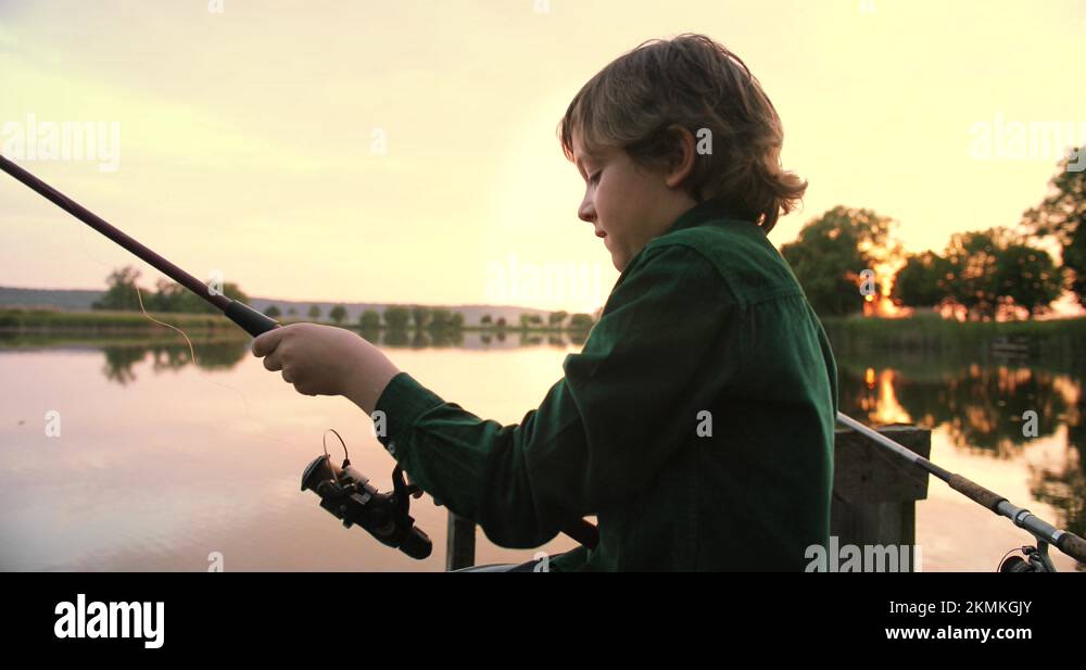 Low angle view of the little teen boy casting a line at the water while ...