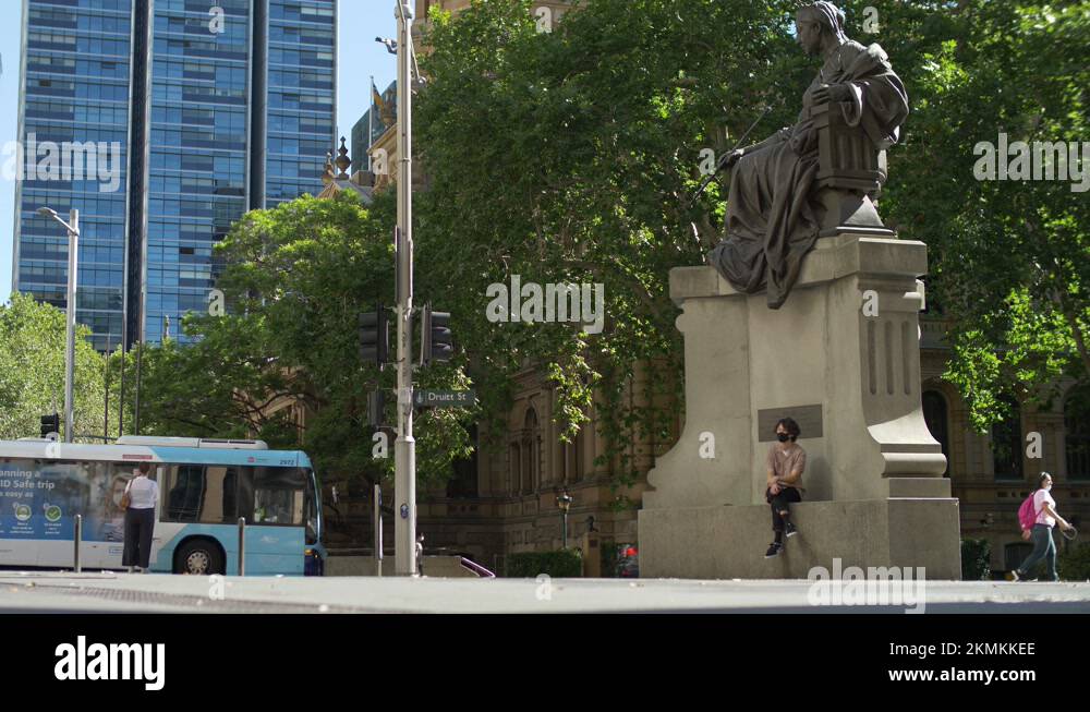 Mask wearing woman sat under Queen Victoria statue in Sydney slow ...