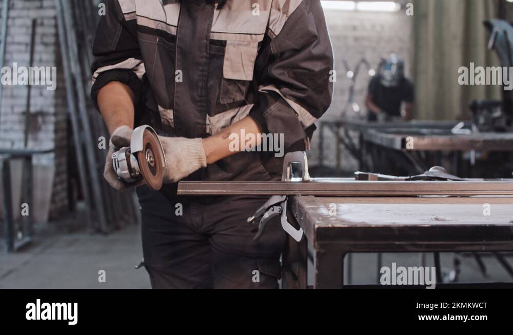 Young man with long hair working at the manufacturing plant - grinding ...