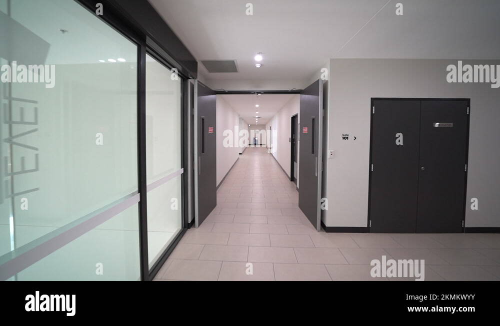 Long hallway of modern office building with white walls, dolly forward ...