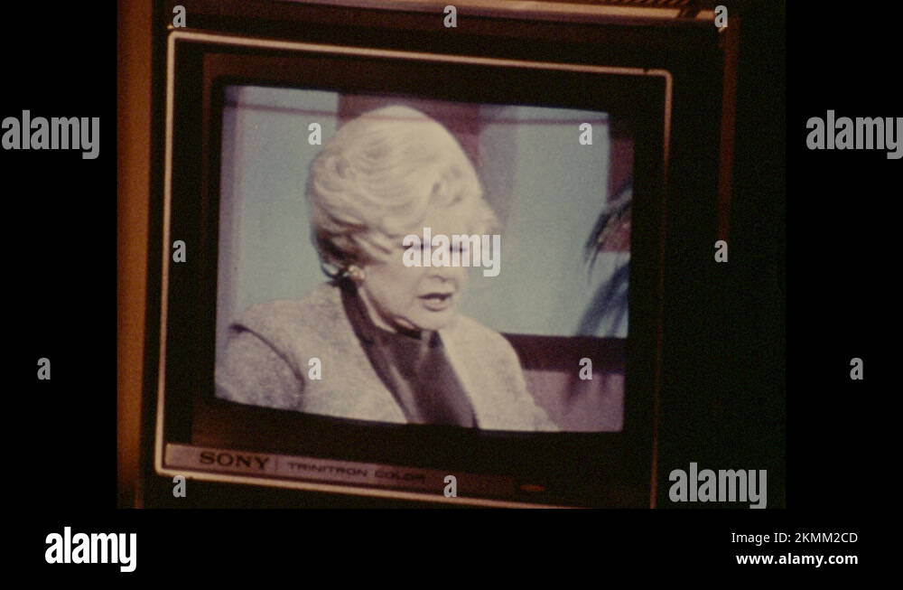 1970s: People speak on small television screen. Hand places ring in ...