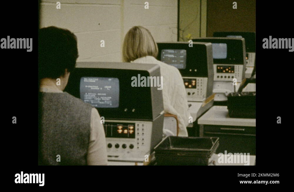 1970s: People type on computers in rows. Computer screen. People in ...