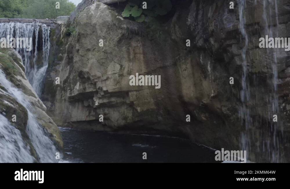 pan out of a large rock formation with multiple water streams falling ...