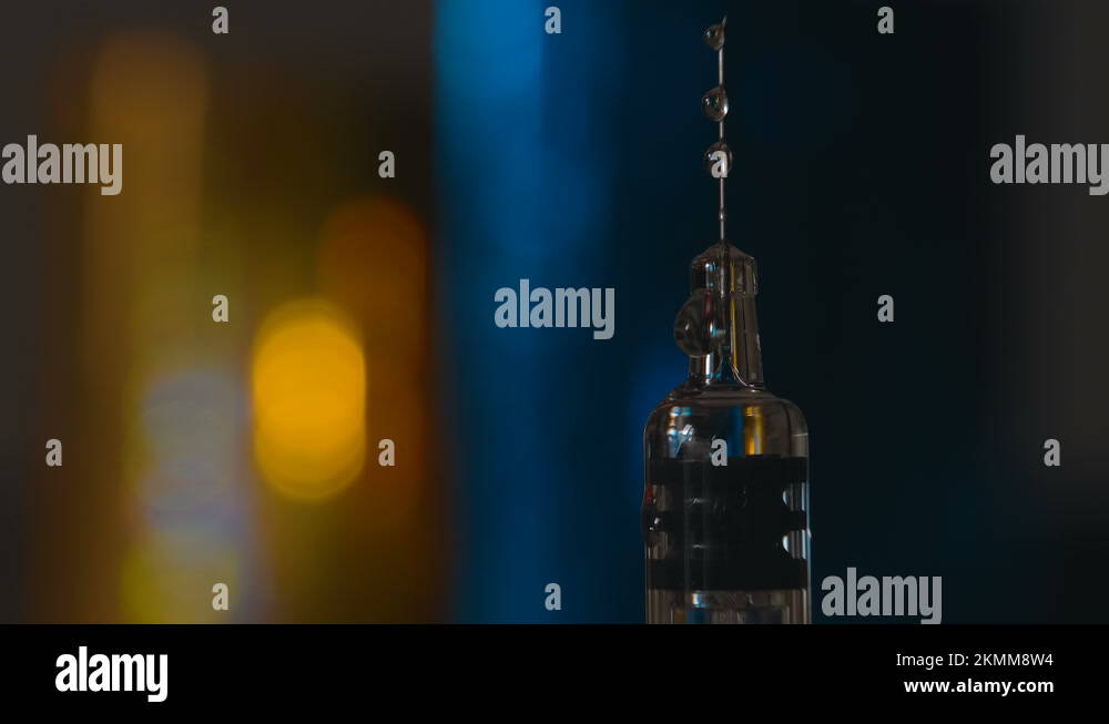 Drops of medicine dripping down the needle of a glass modern syringe ...