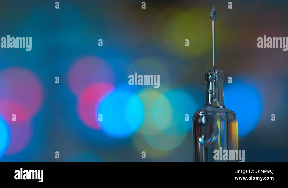 Drops of medicine dripping down the needle of a glass modern syringe ...