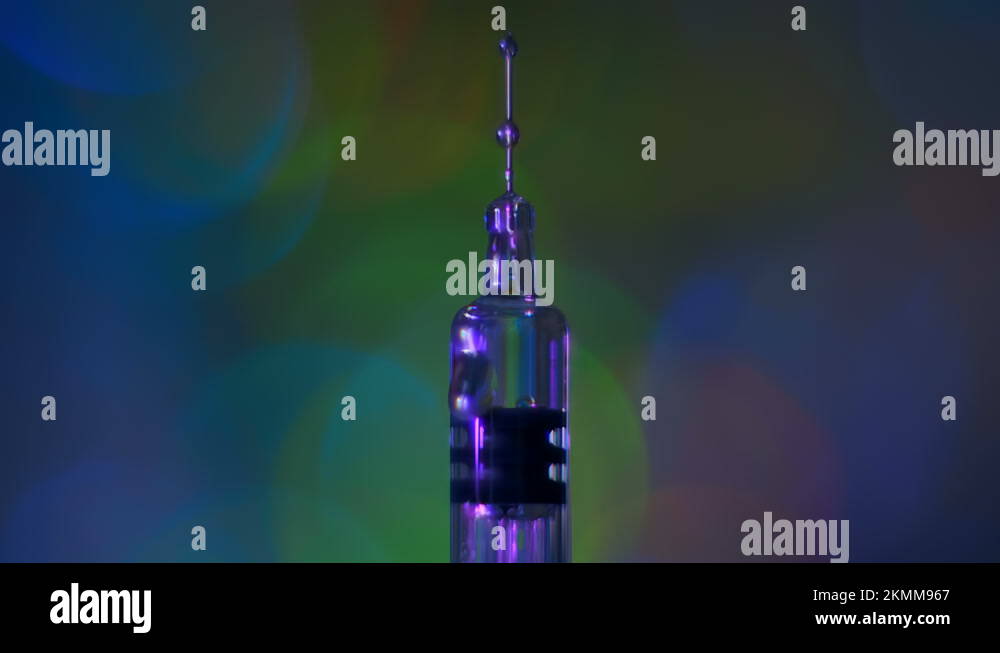 Drops of medicine dripping down the needle of a glass modern syringe ...