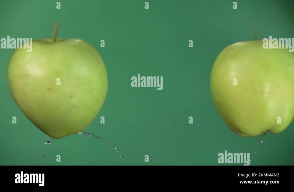 Two apples are flying towards each other, colliding on the green ...