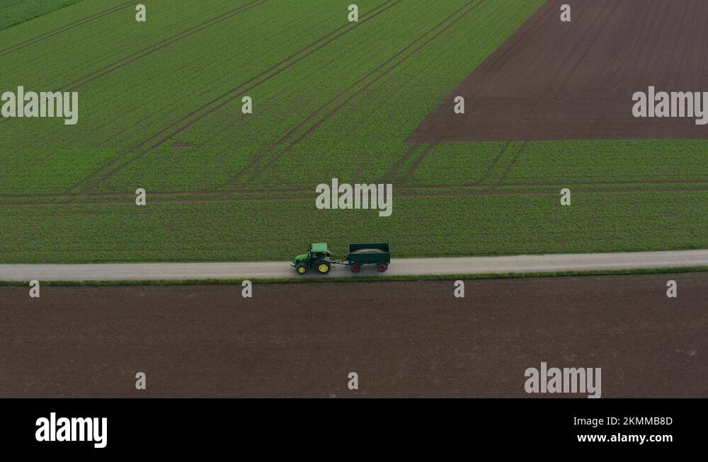 A tracked tractor is driving slow to the left side along a country road ...