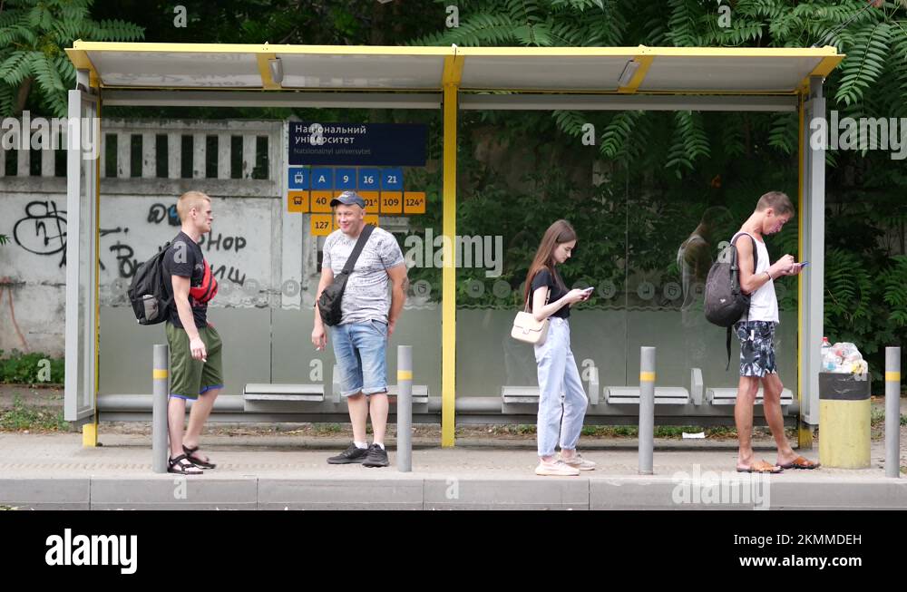 People stand at a bus stop waiting for public transport to arrive Stock ...
