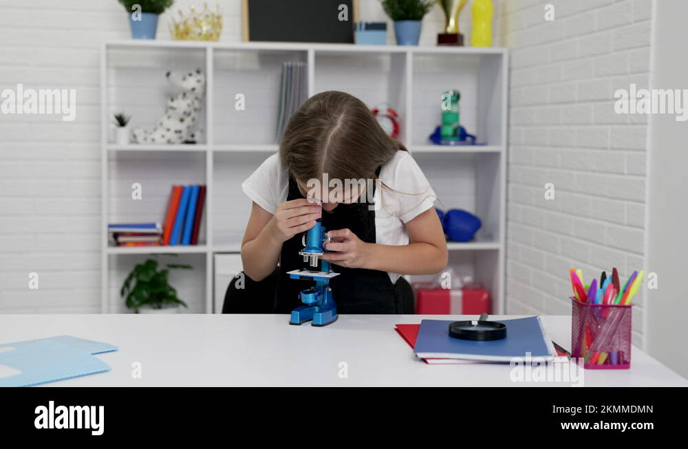 curious teen girl looking through microscope on biology lesson, school ...
