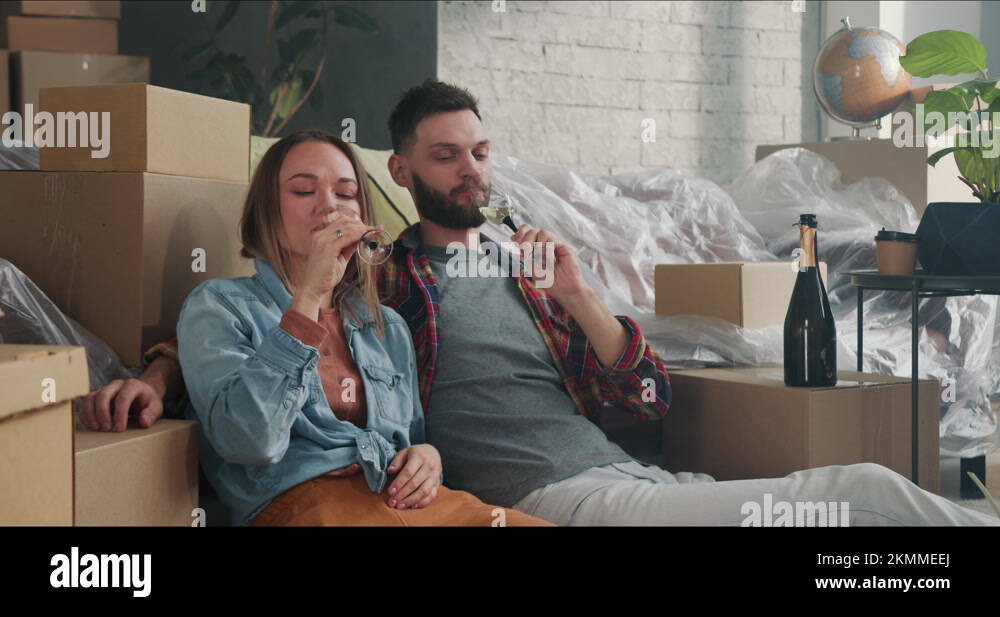 Young happy couple moving in new home sitting on floor relaxing after ...