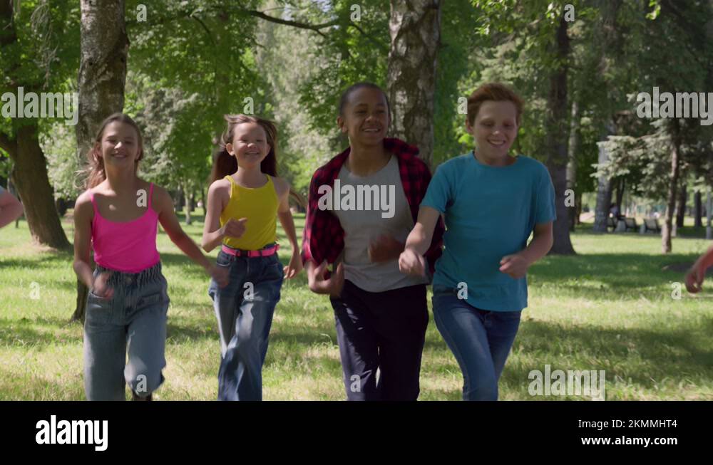 Slider shot of diverse happy kids playing catch-up game and running in ...