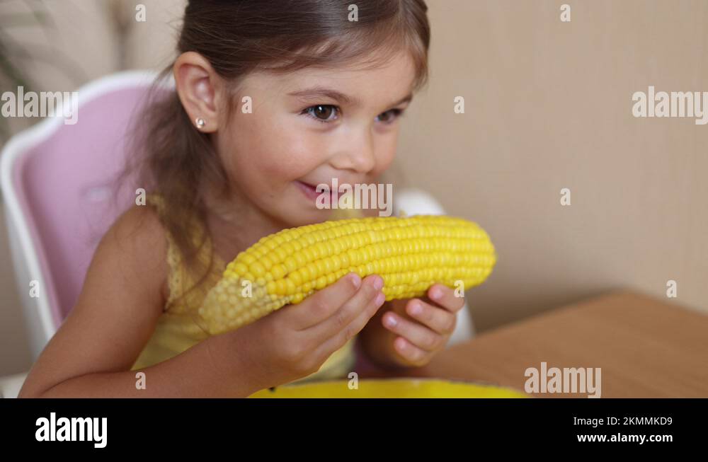 Adorable little girl eating corn at home. Cute kid tree year old eat ...
