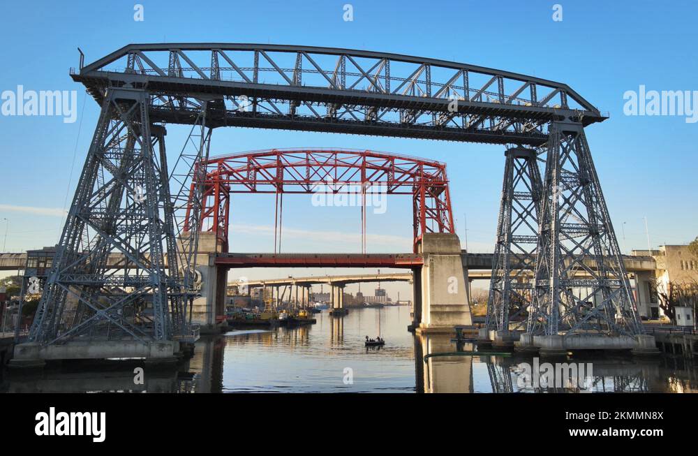 Slow low pan of Puente Transbordador, other bridge and boat in water ...