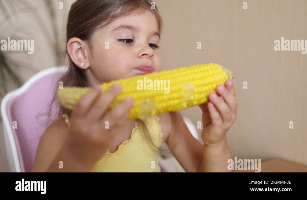 Adorable little girl eating corn at home. Cute kid tree year old eat ...