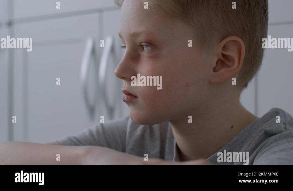 Close up portrait of battered teen boy crying from abuse, sitting alone ...