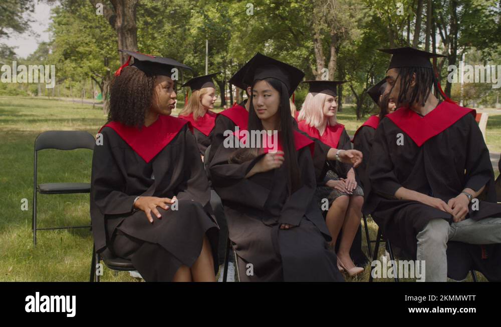 Happy multiracial classmates greeting each other at graduation ceremony ...