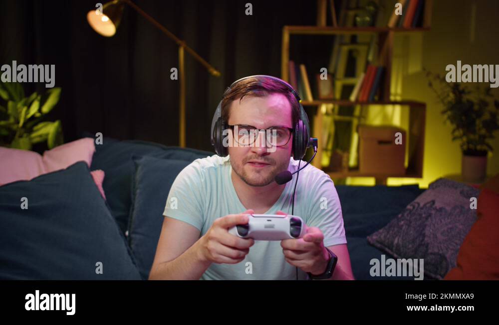 Young man gamer wearing headphones with microphone playing video game ...