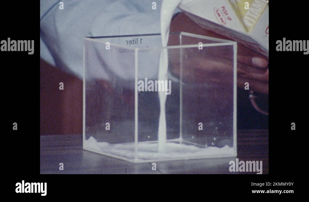 1970s: Boy and girl carry milk carton to table. Hands pour milk into ...