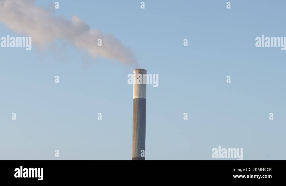 Air pollution smoke rising from a fossil fuel power plant chimney ...