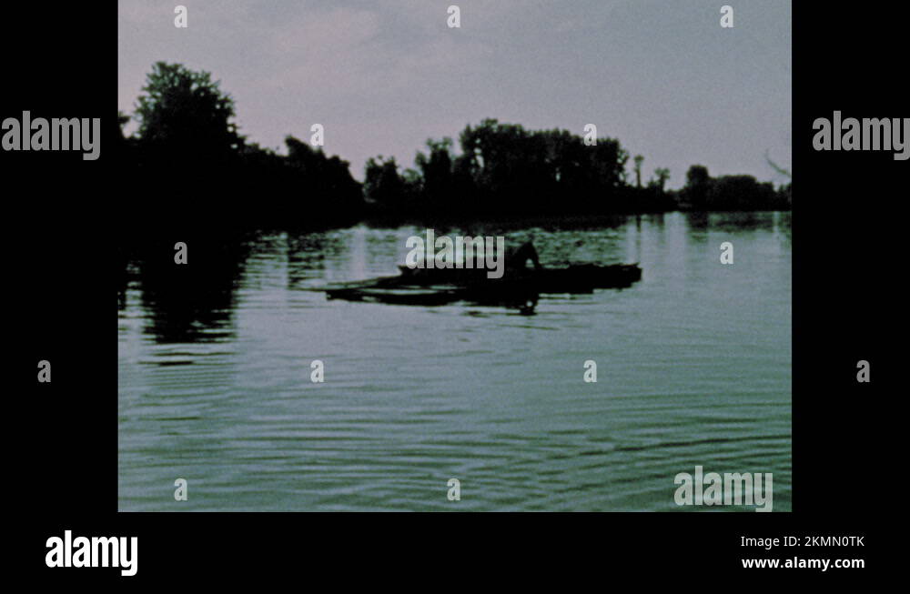 1970s: Man and boy on raft going down river. Man and boy lay on raft ...