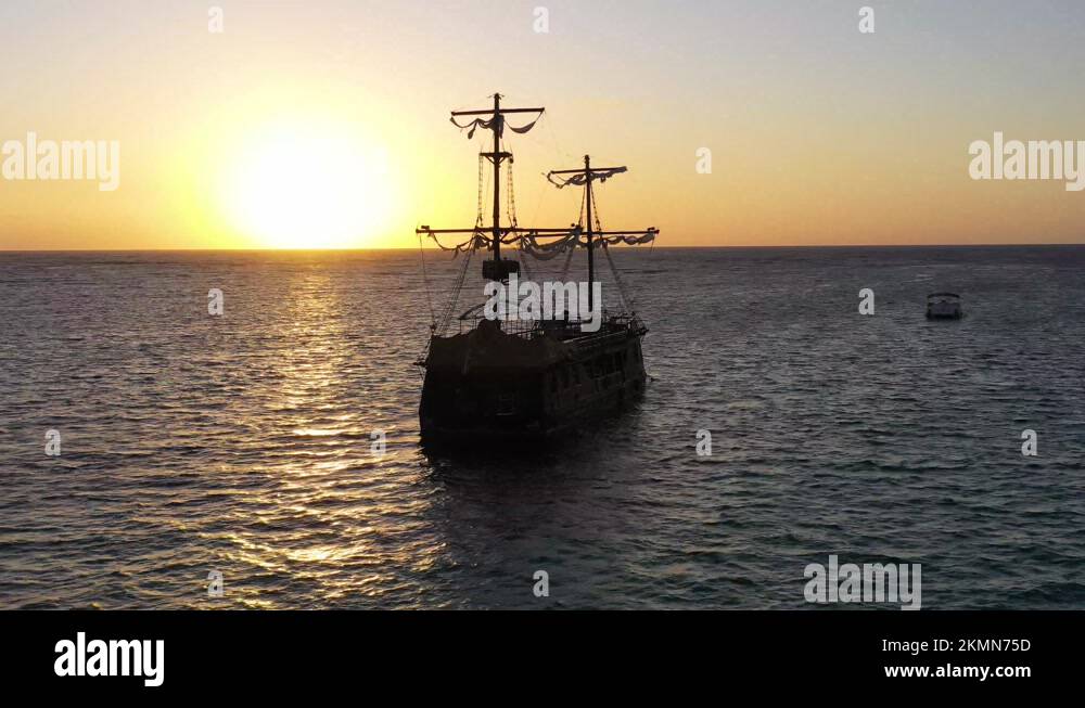Pirate ship tour boat anchored with sun setting in the ocean, Aerial ...