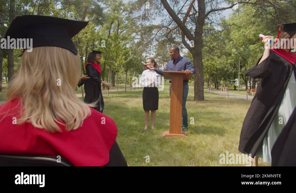 Happy multiracial graduates receiving diplomas from dean at graduation ...