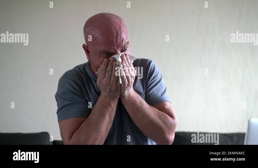 Unhealthy bald man. Guy is sick with flu, sneezes and blows his nose ...