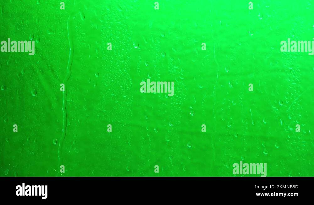 Close-up of the water drops rolling down a clear glass, green screen ...