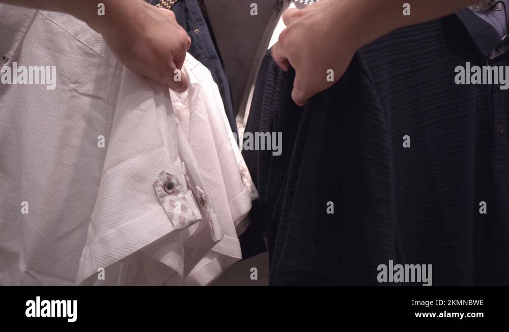 A man chooses clothes in a shop, shopping. Selection of T-shirts and ...