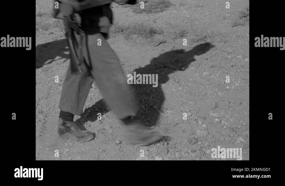1940s: Soldiers run across desert holding rifles at ready. Different ...