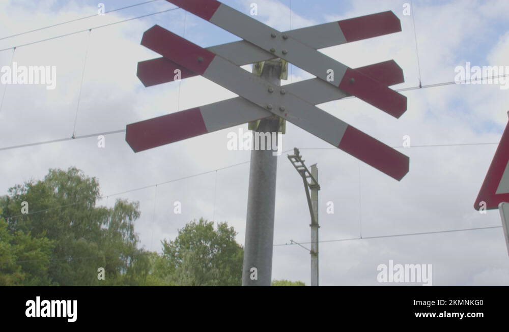 tilt up to red white railroad crossing sign indicating multiple tracks ...