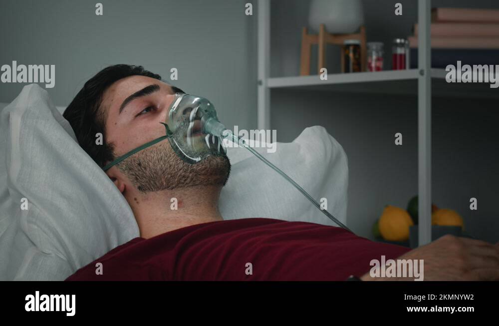 Sick patient lying with oxygen mask in hospital ward, serious bad human ...
