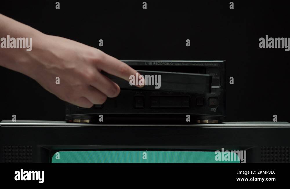 Putting video cassette into recorder. Old retro television with blue ...