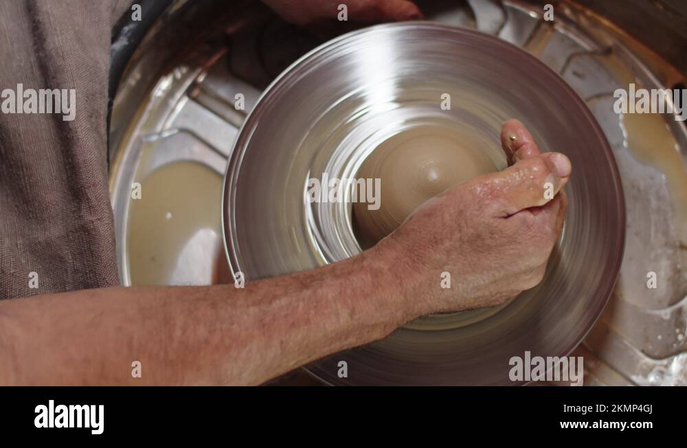 Potter gives round shape to future pottery with two hands, using potter ...