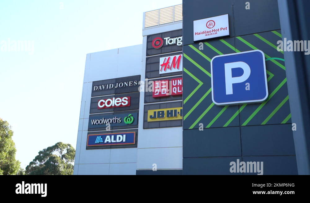 Shopping building exterior with different stores logos and parking lot ...