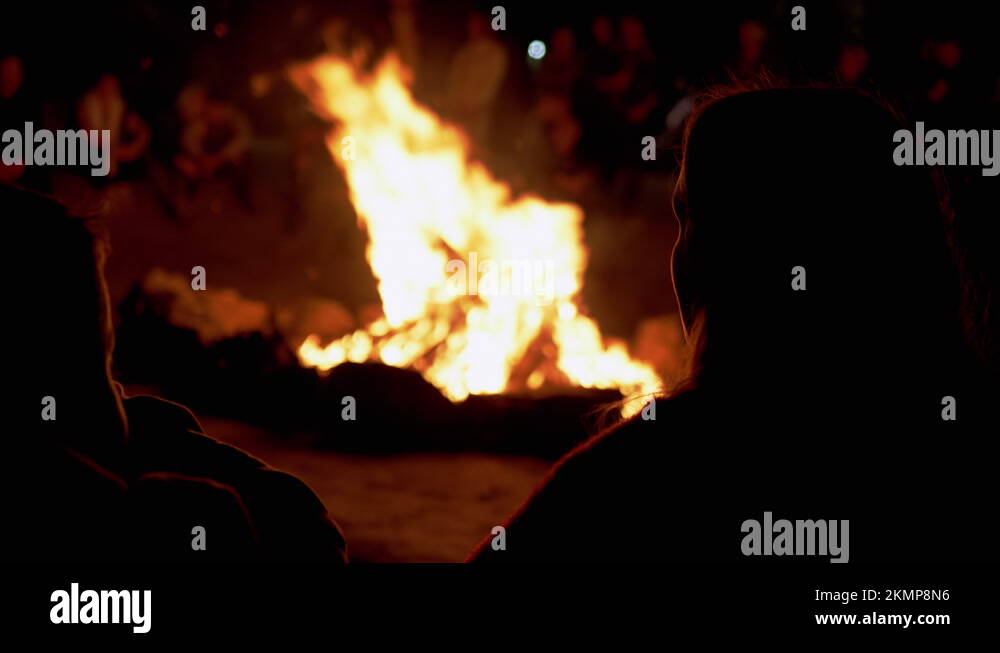 Silhouettes of a Woman and a Child Looking at a Large Bonfire in Night ...