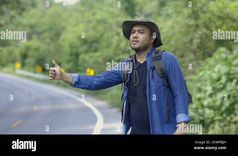 Pick me up. Man hitchhiking on the side of the road. Man try stop car ...