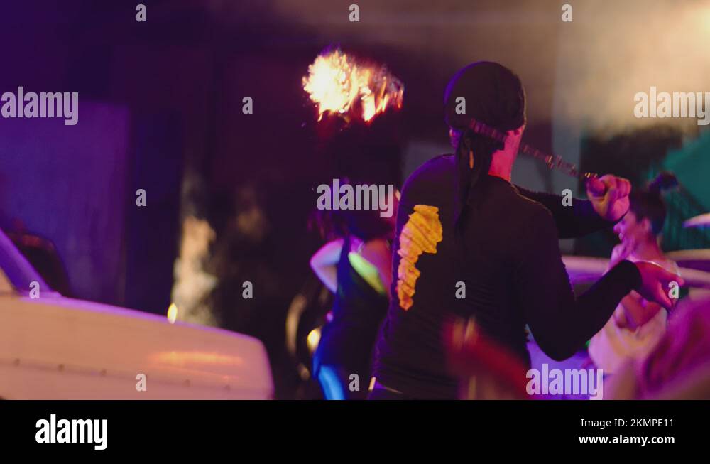 Man performing fire show with fire burning iron chain at night . Girls ...