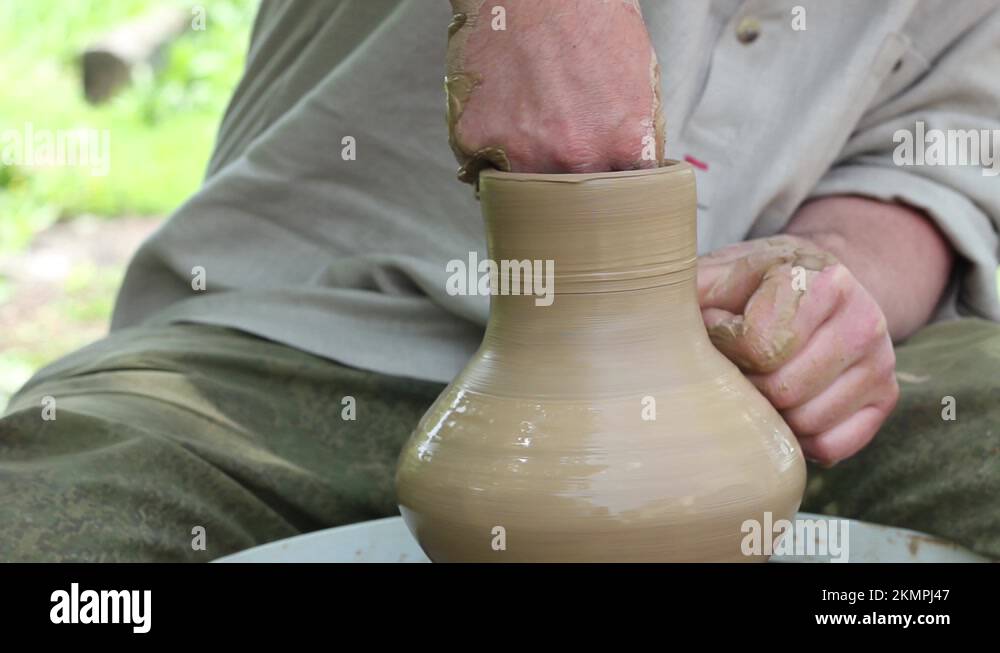 male potter of Caucasian ethnicity makes a clay jug on an automatic ...