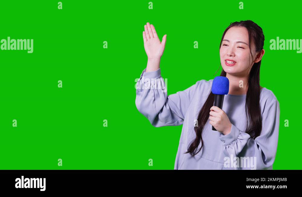 Young asian woman talking with a microphone. TV reporter. Green ...