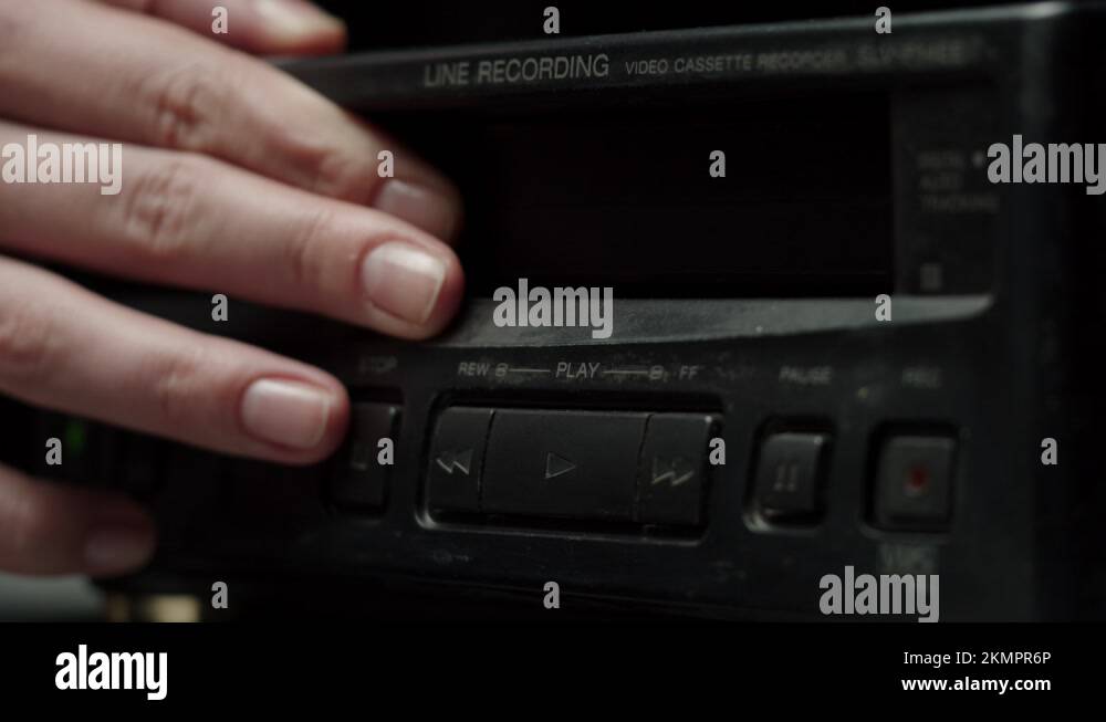 Putting video cassette into recorder. Old retro television with blue ...