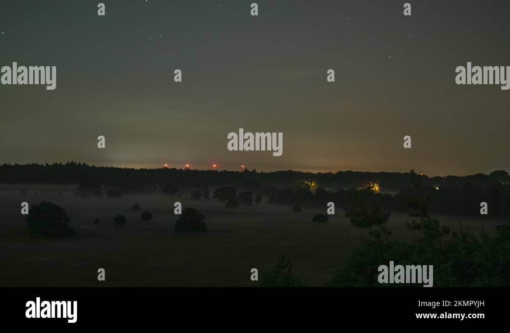 City lights, rolling fog on ground and majestic starry sky timelapse ...