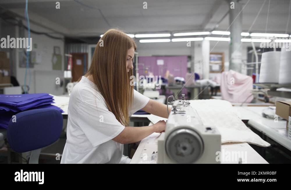 Happy attractive young woman seamstress sitting and sews on sewing ...