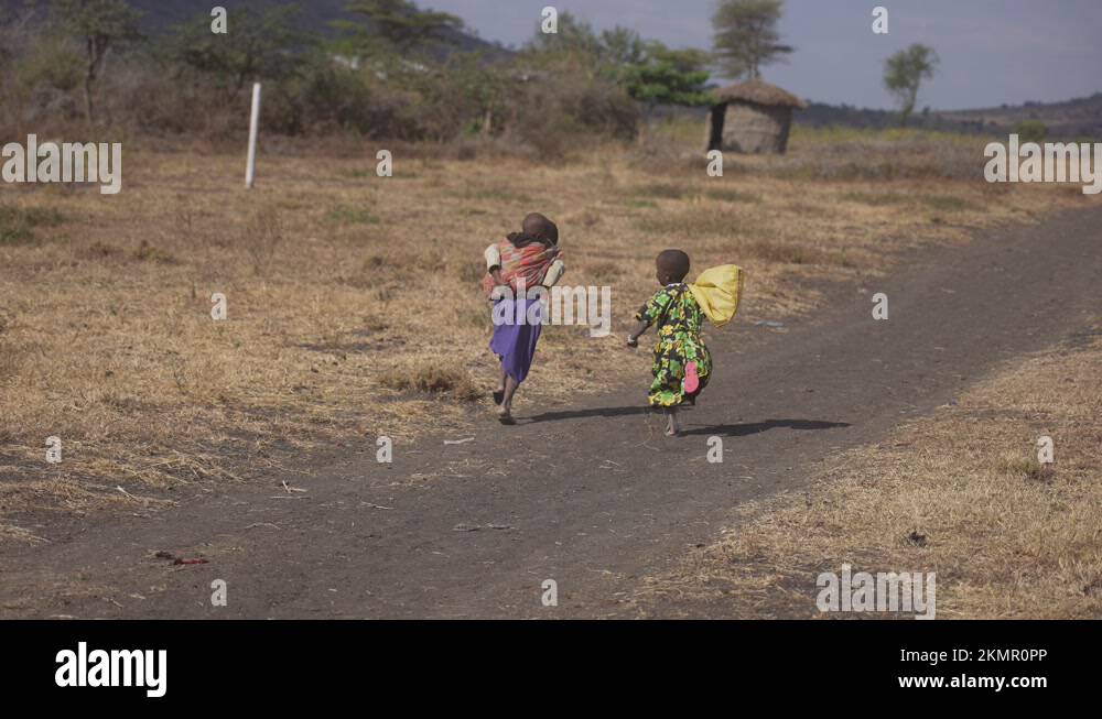 Two poor African happy children running in a rural village. Nature and ...