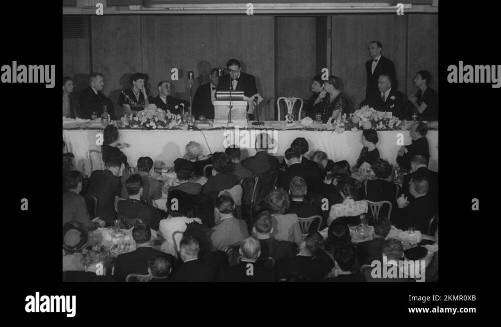 1940s: Man gives a speech to a crowded room, with people sitting around ...